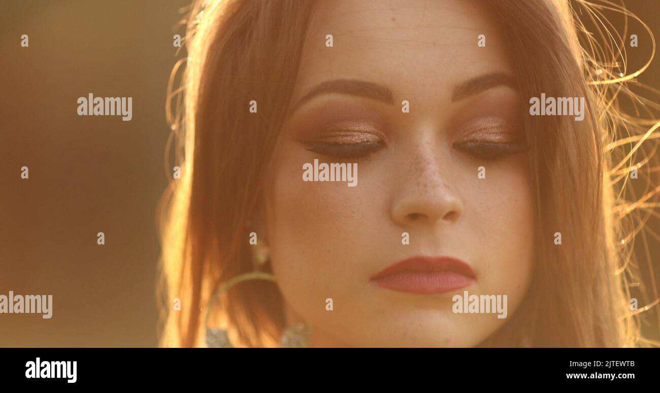 Pensive young woman during dreamlike golden hour sunset time ...