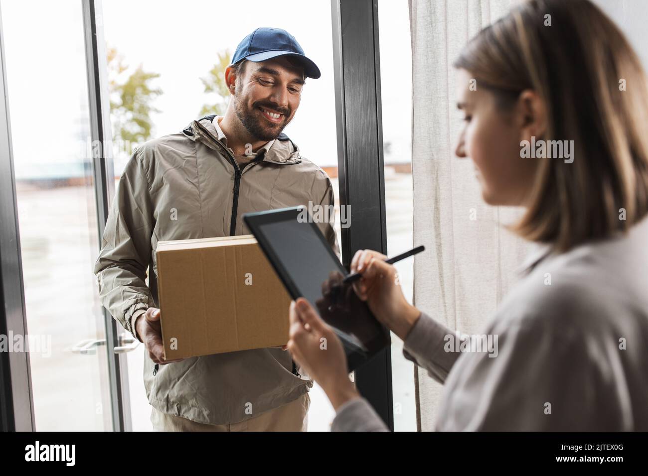delivery man with box and woman signs digital form Stock Photo - Alamy