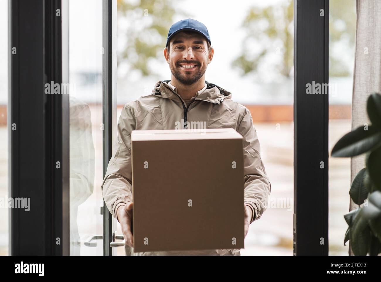 smiling delivery man with parcel box at open door Stock Photo - Alamy