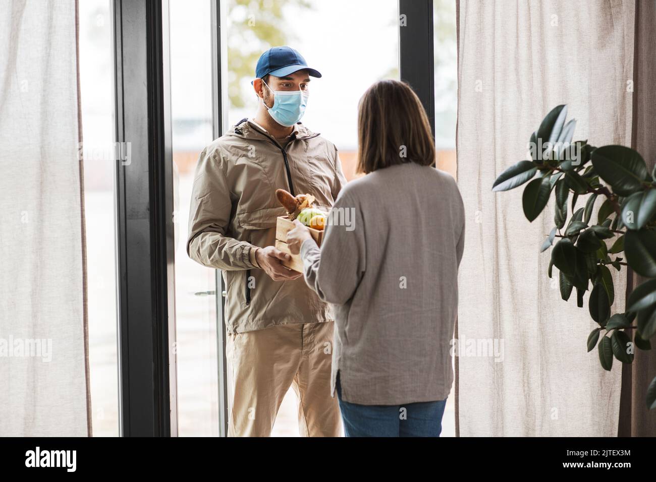 food delivery man in mask giving order to customer Stock Photo - Alamy