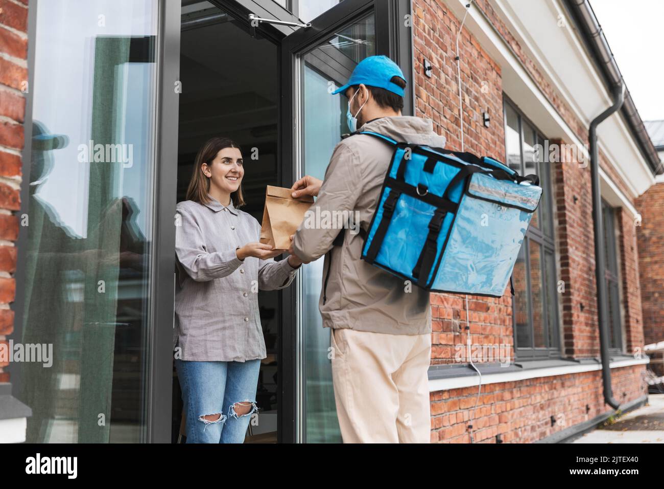 food delivery man in mask giving order to customer Stock Photo - Alamy