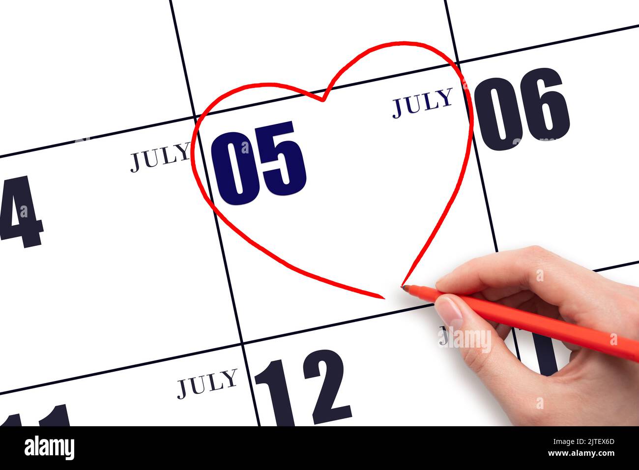 5th day ofJuly. A woman's hand drawing a red heart shape on the ...