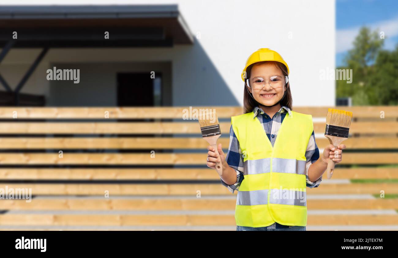 girl in helmet and safety vest with paint brush Stock Photo - Alamy