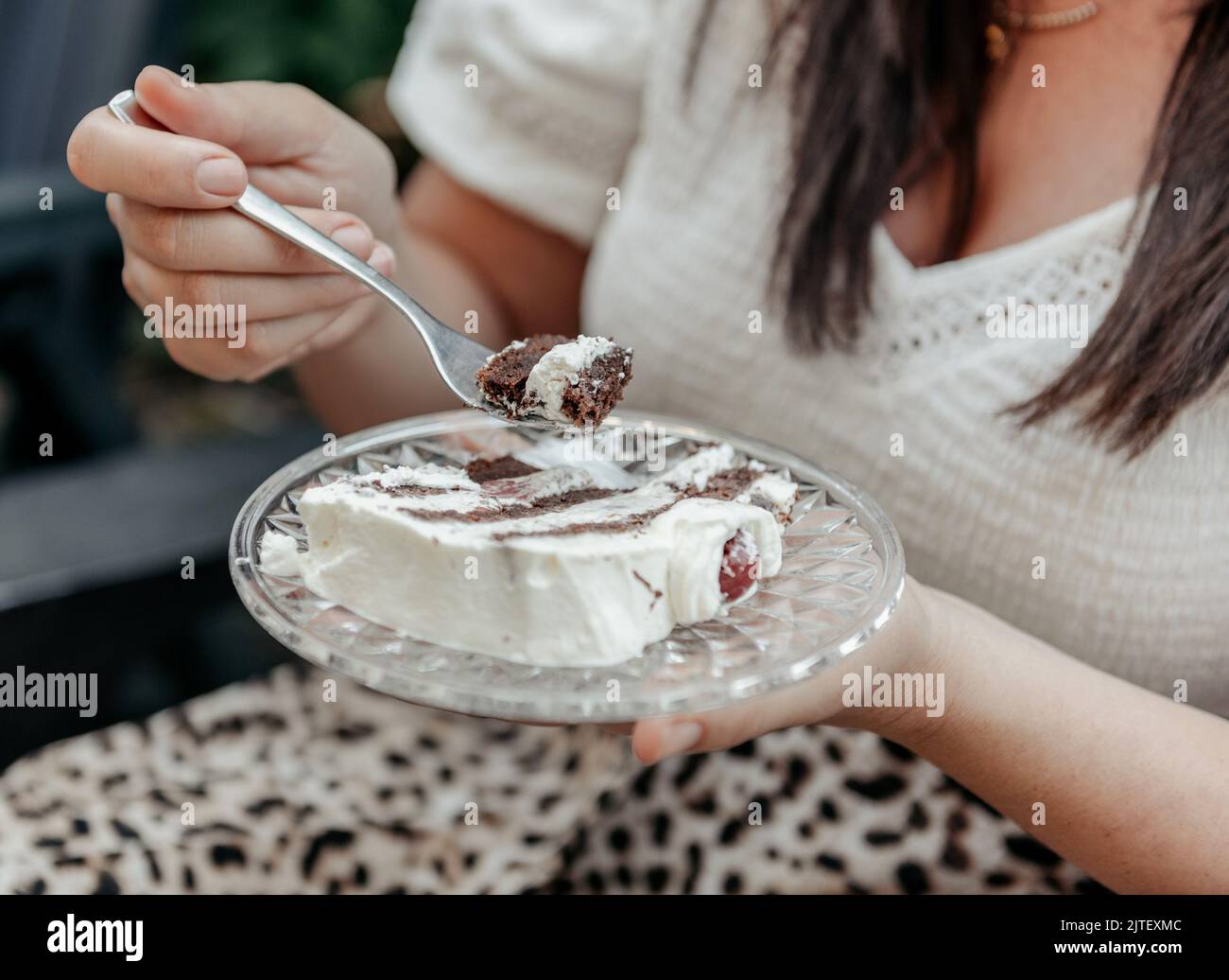 A closeup shot of a female sitting and eating a slice of cake Stock ...