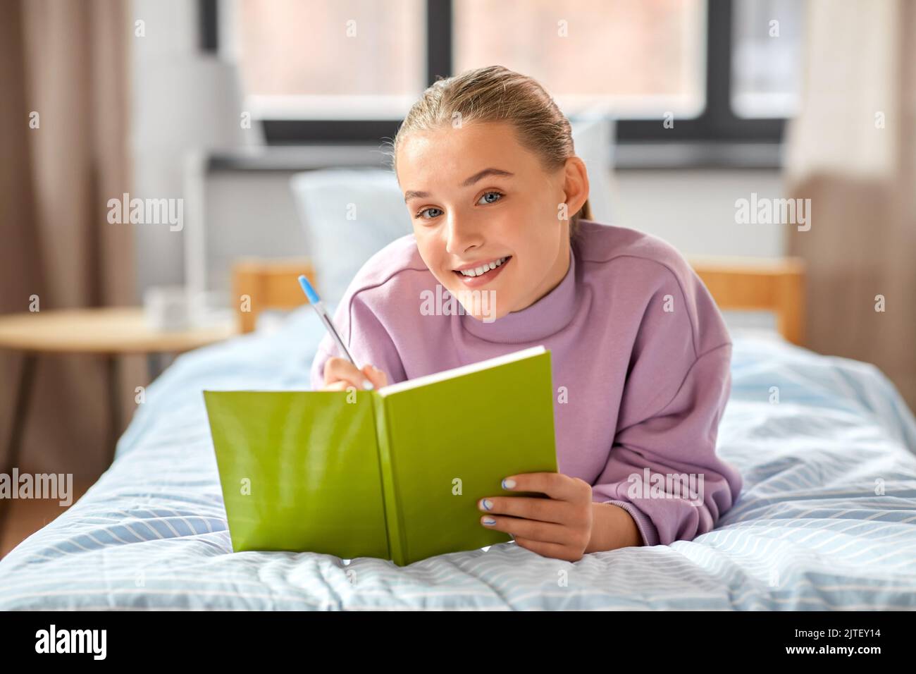 girl lying on bed and writing to diary at home Stock Photo - Alamy