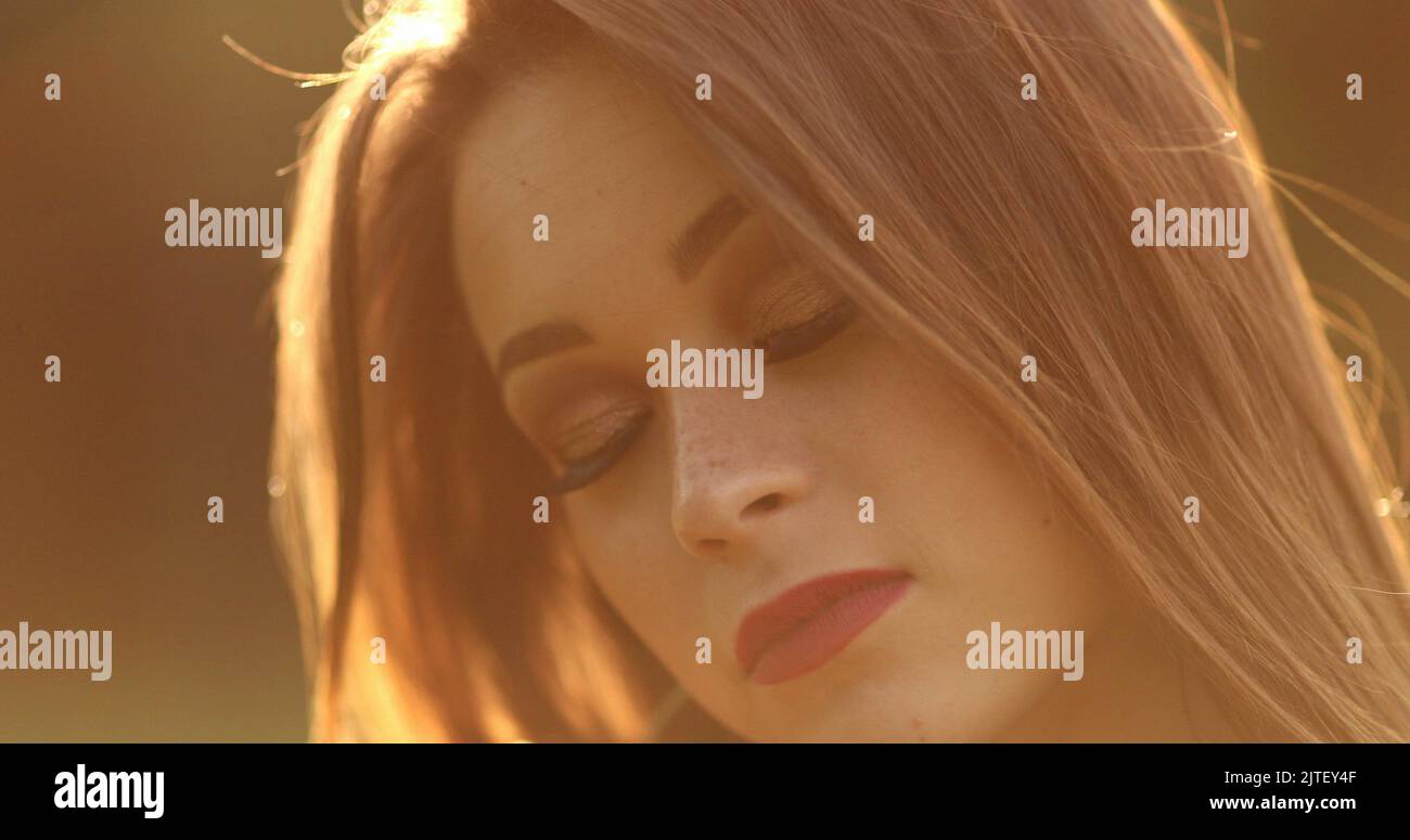 Pensive young woman during dreamlike golden hour sunset time ...