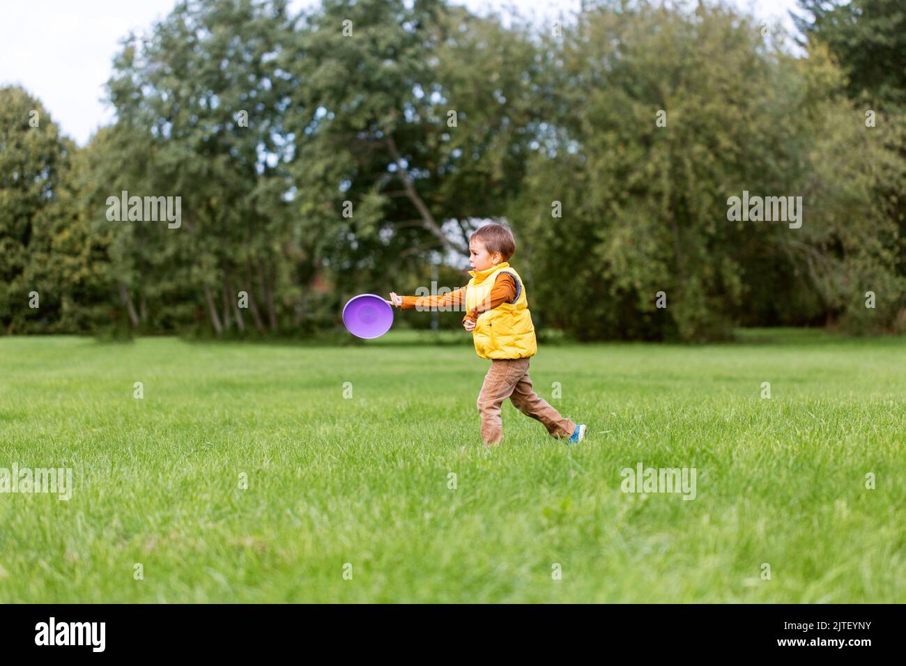 happy little boy playing with flying disc at park Stock Photo - Alamy