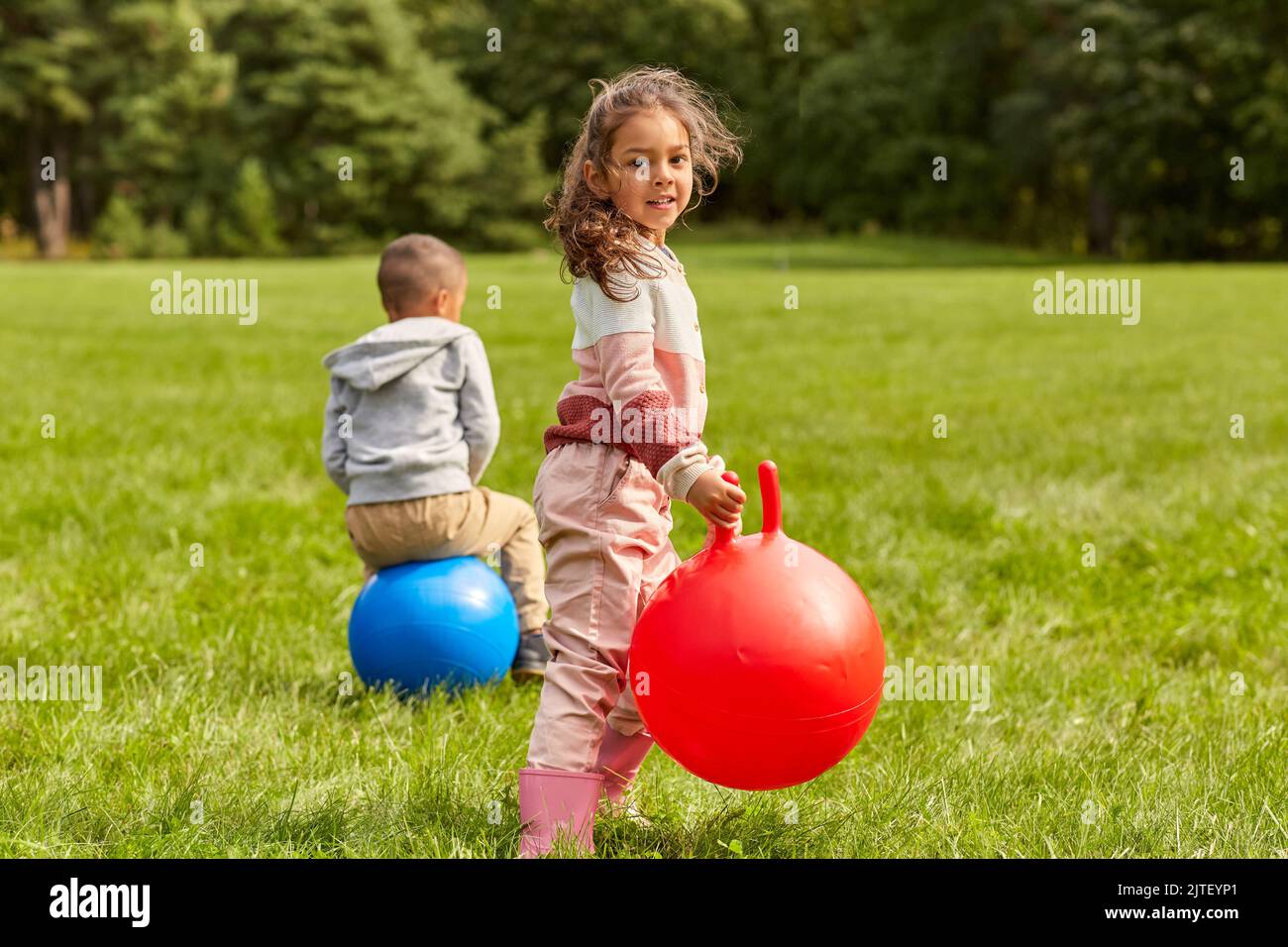 happy children bouncing on hopper balls at park Stock Photo - Alamy