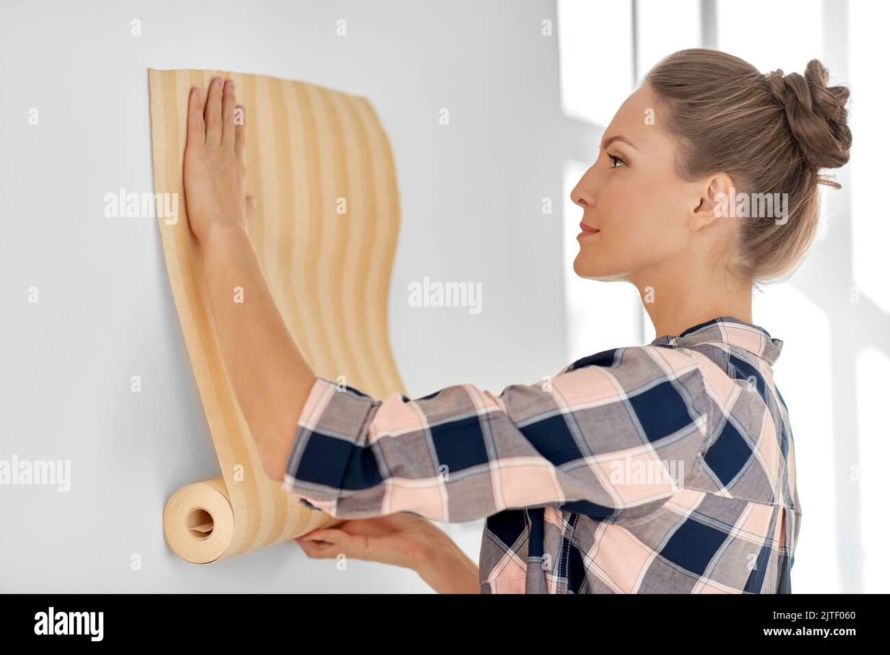 woman applying wallpaper to wall at home Stock Photo - Alamy