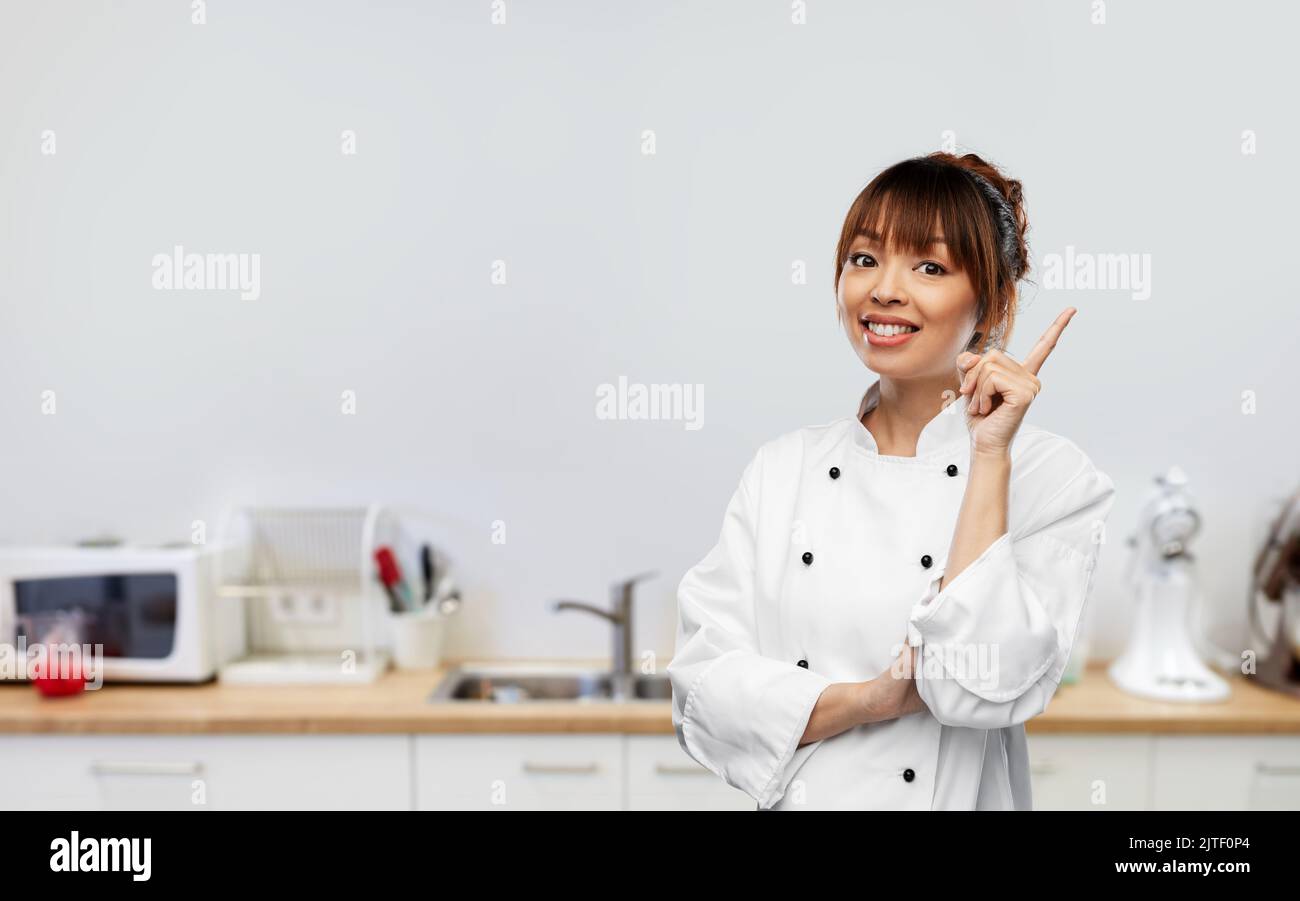smiling female chef pointing finger up on kitchen Stock Photo - Alamy
