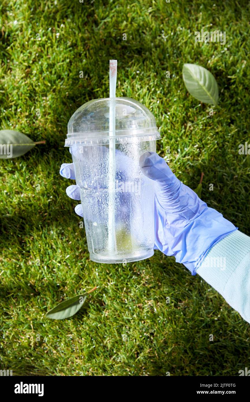 hand in glove removing plastic cup from grass Stock Photo - Alamy