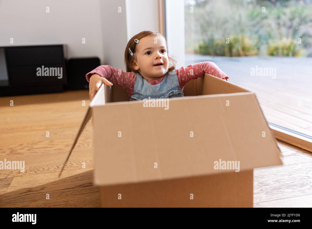 little baby girl sitting in cardboard box at home Stock Photo - Alamy