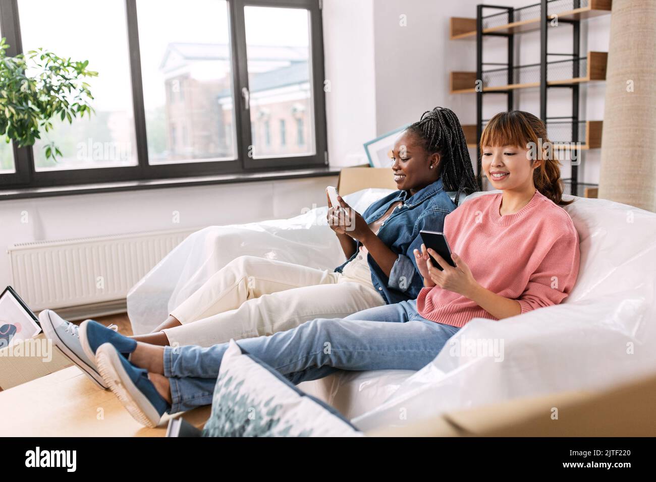women with smartphones moving into new home Stock Photo - Alamy