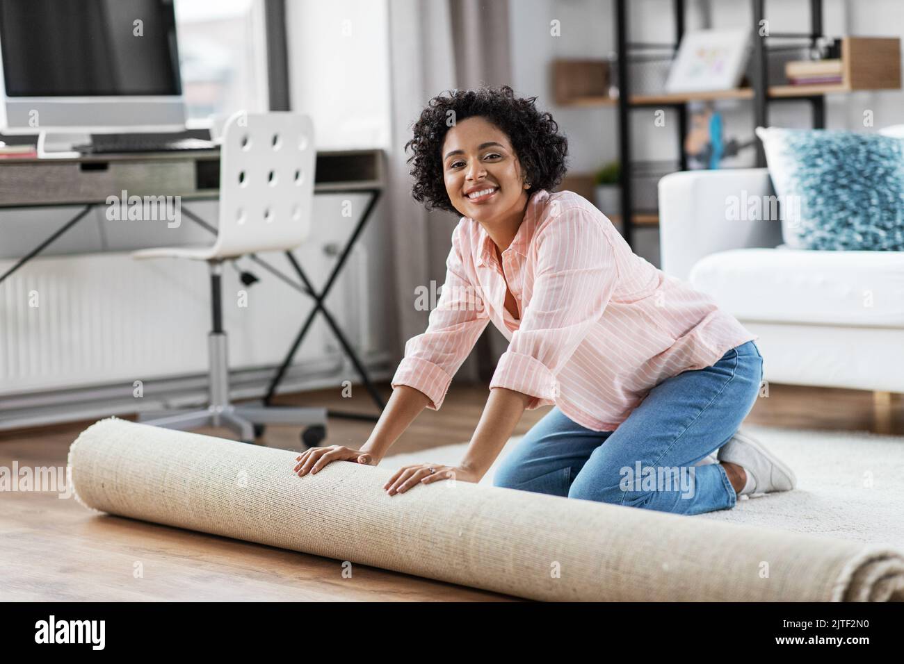 young woman unfolding carpet at home Stock Photo - Alamy