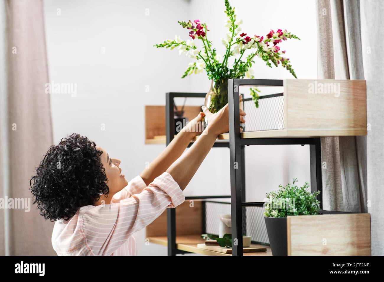 Woman putting flowers on shelving hi-res stock photography and images ...