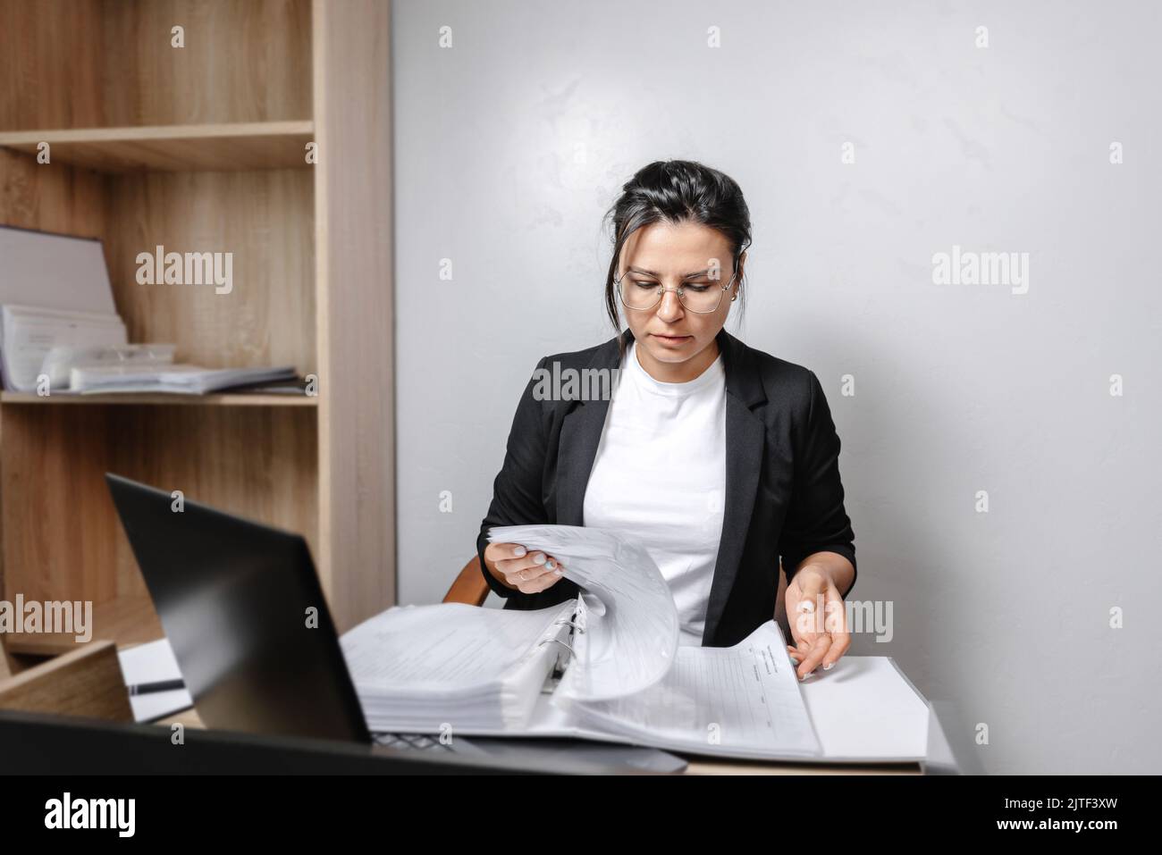 Image of a woman jotting down notes while sitting at a desk in an ...