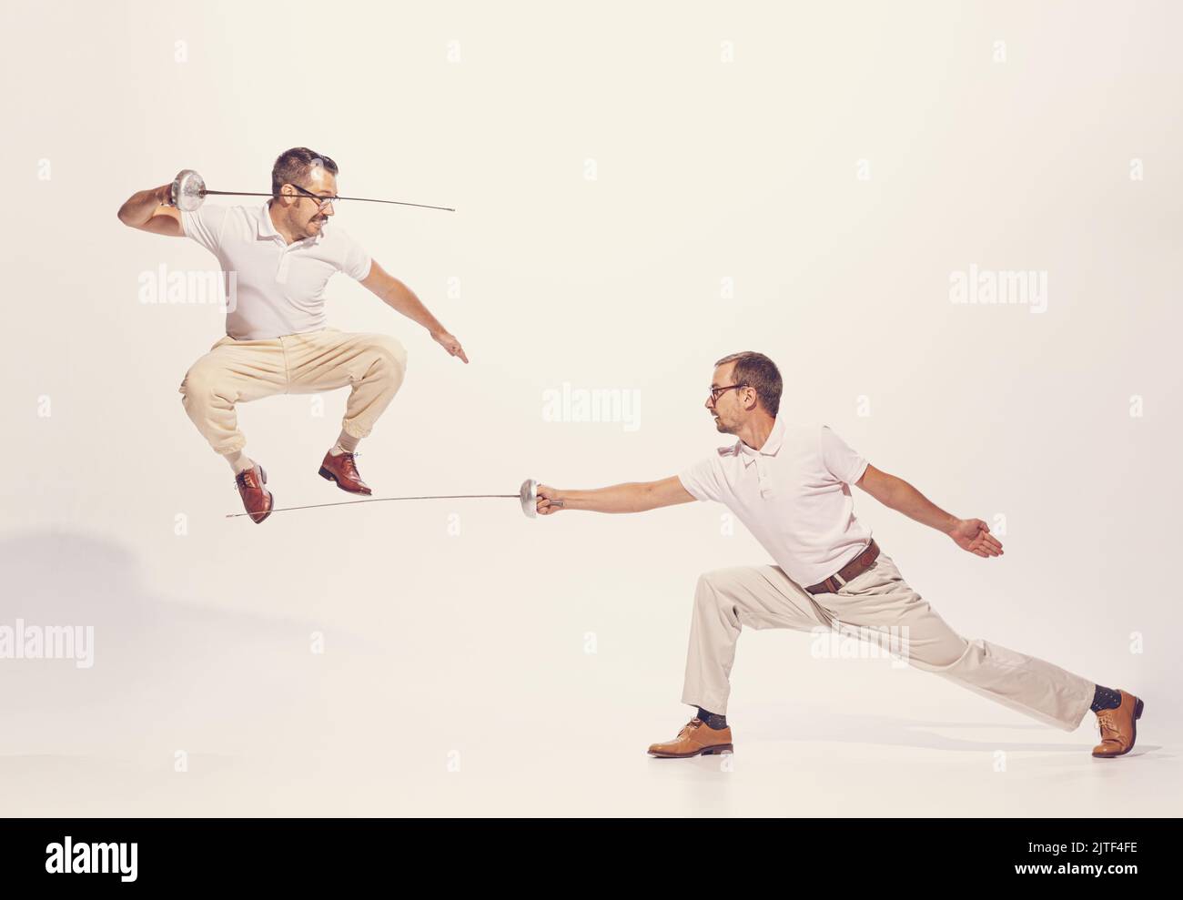 Portrait of two men in a suit fighting with swords, posing isolated ...