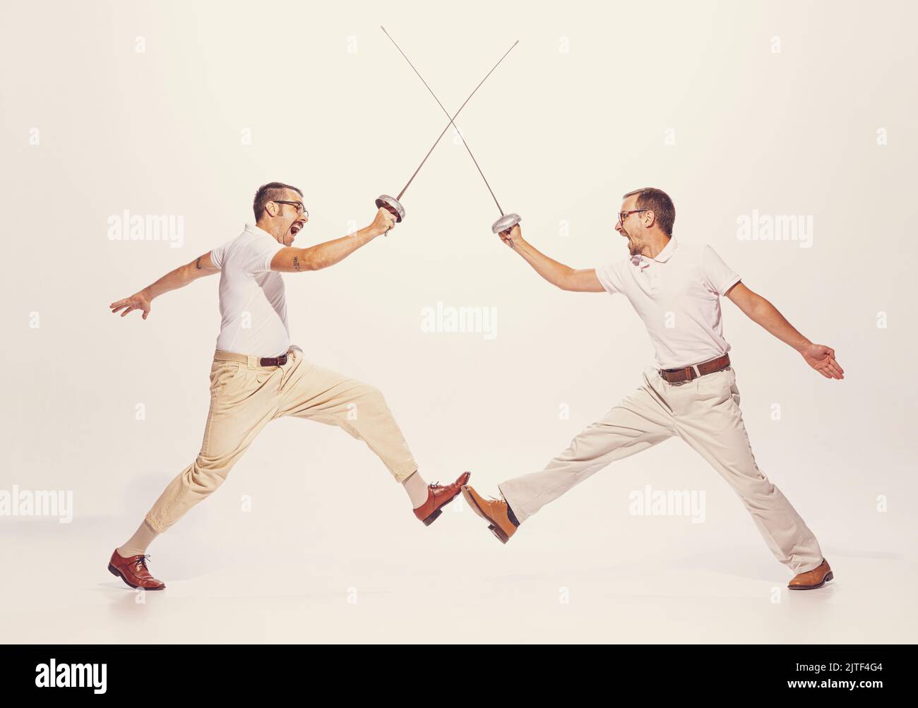 Portrait of two men in a suit fighting with swords isolated over grey ...
