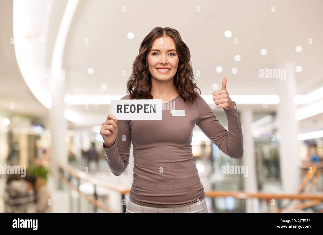 shop assistant with reopen sign showing thumbs up Stock Photo - Alamy
