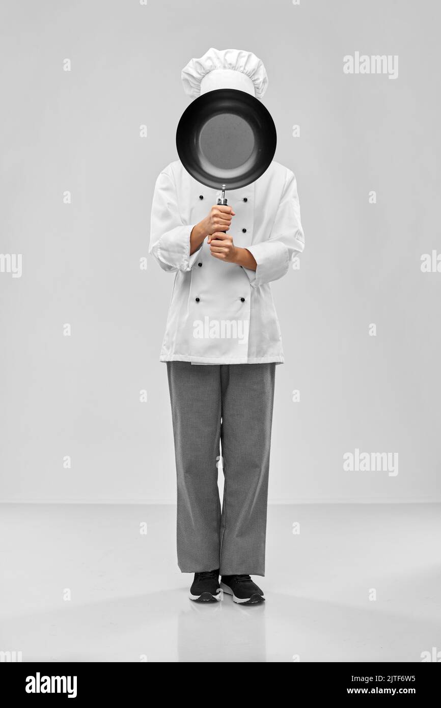 female chef peeking out from behind frying pan Stock Photo - Alamy