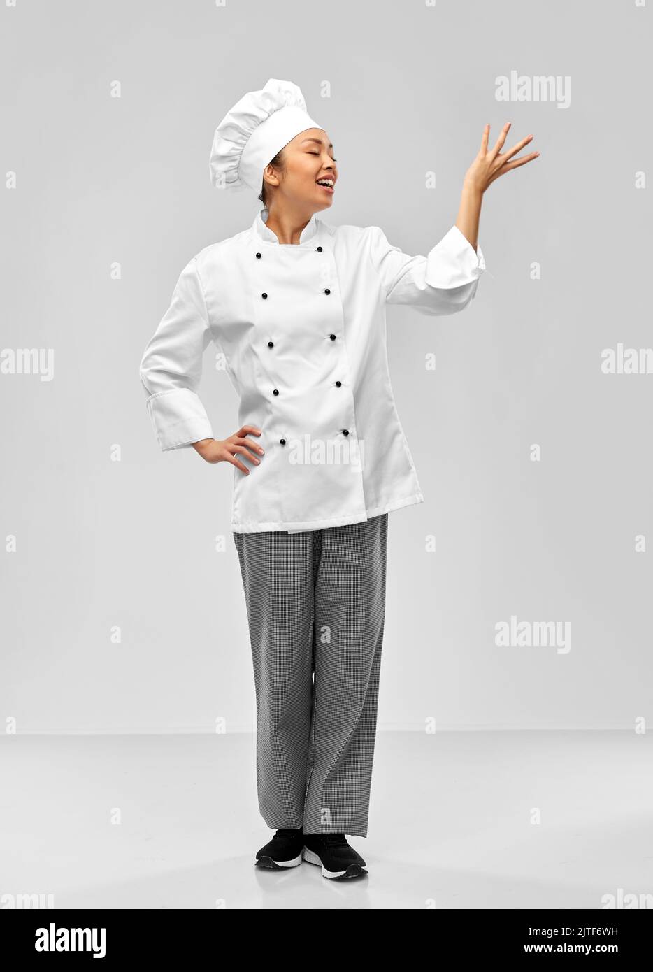 happy female chef posing over grey background Stock Photo - Alamy