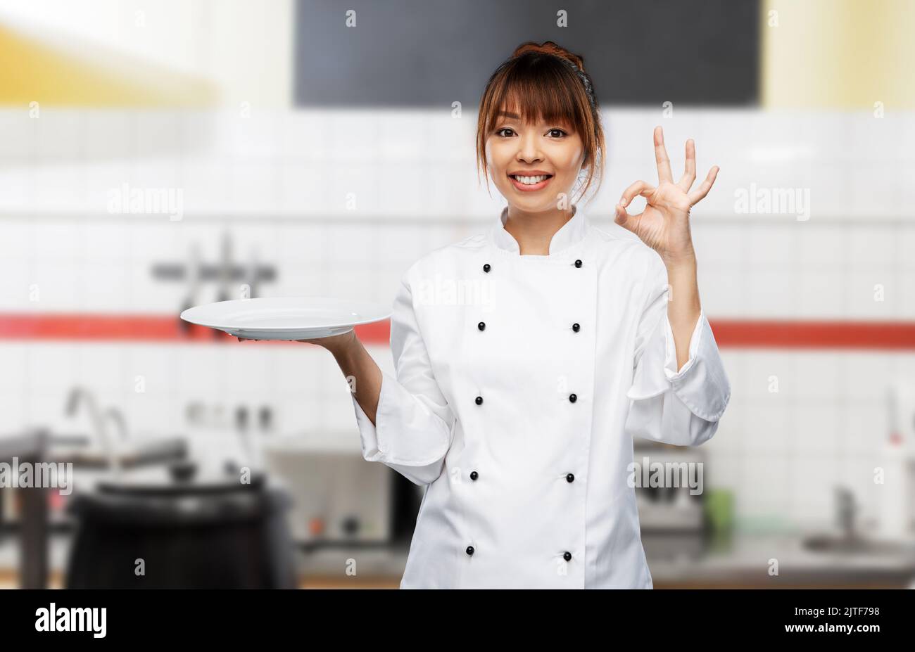female chef holding empty plate and showing ok Stock Photo - Alamy