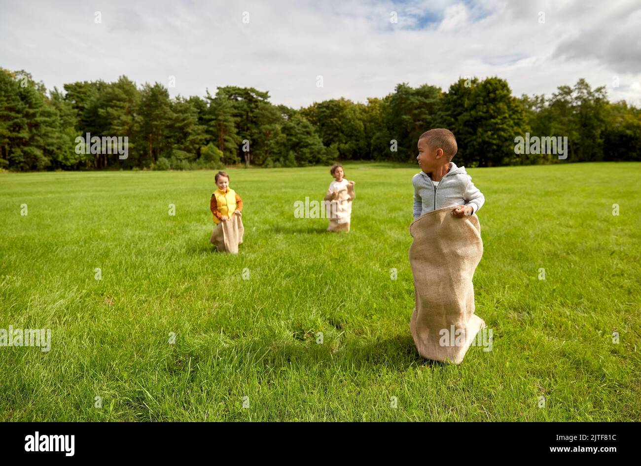 happy children playing bag jumping game at park Stock Photo - Alamy