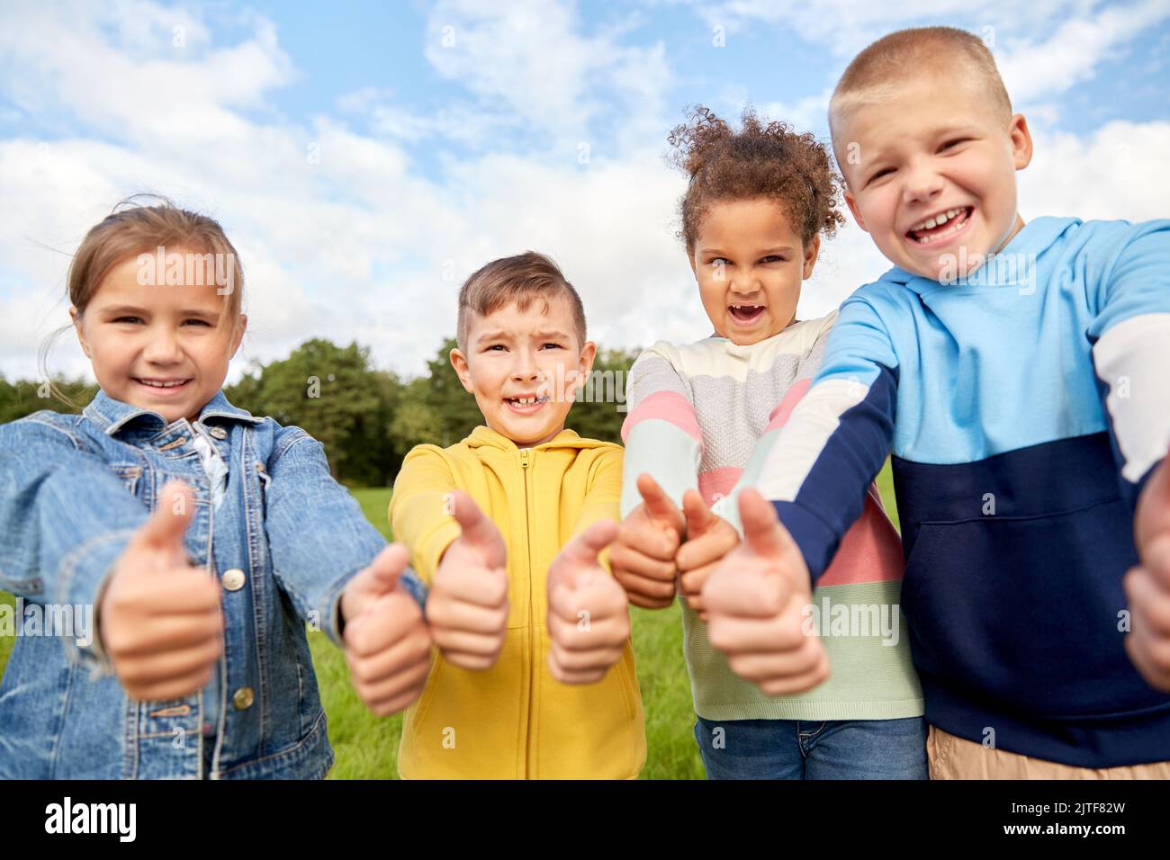 happy children showing thumbs up at park Stock Photo - Alamy