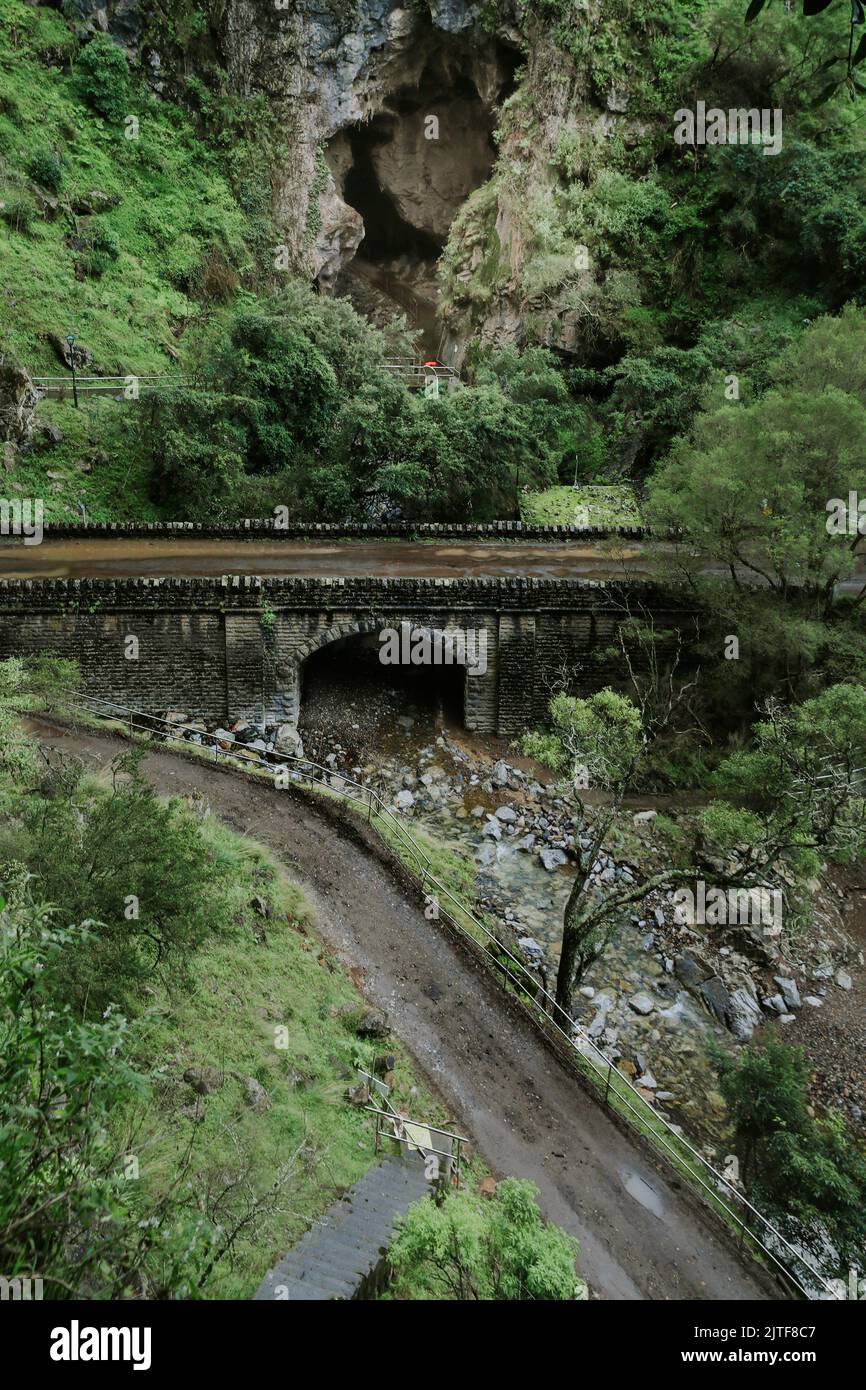 A scenic vertical shot of a stone bridge in the middle of the cliff of ...