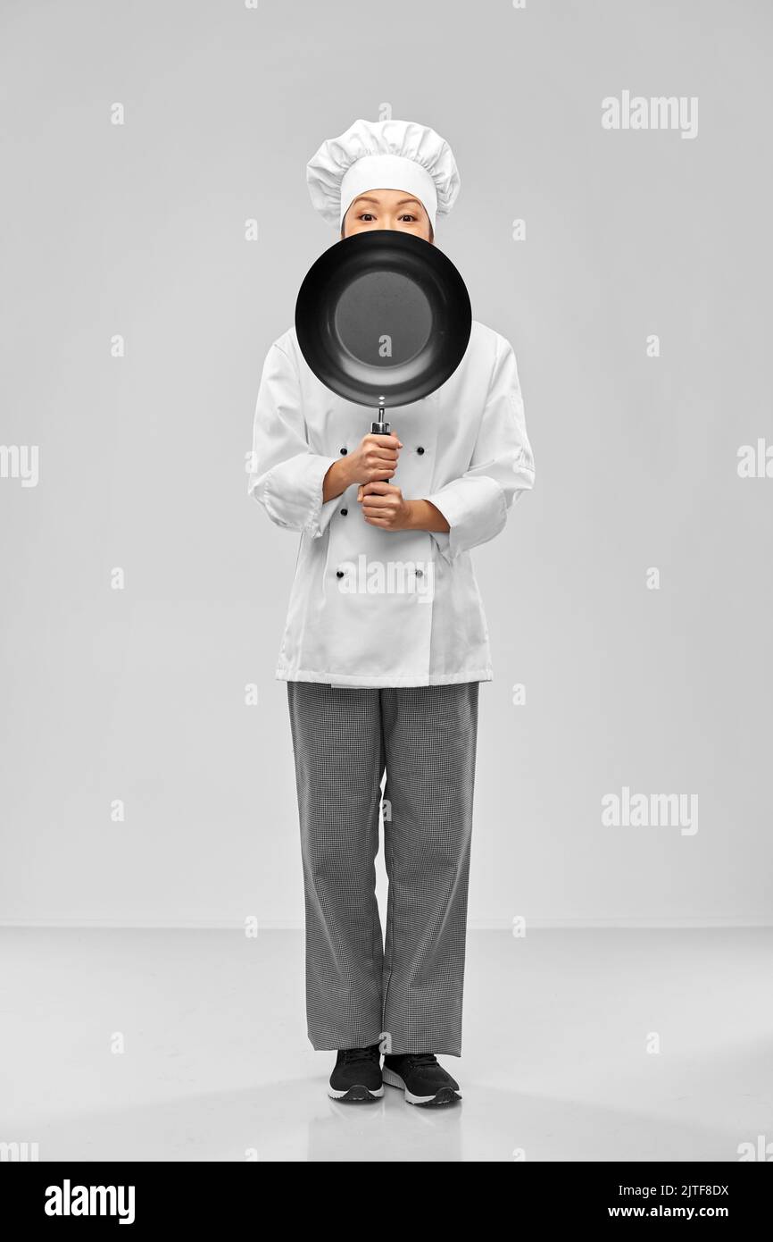 female chef peeking out from behind frying pan Stock Photo - Alamy