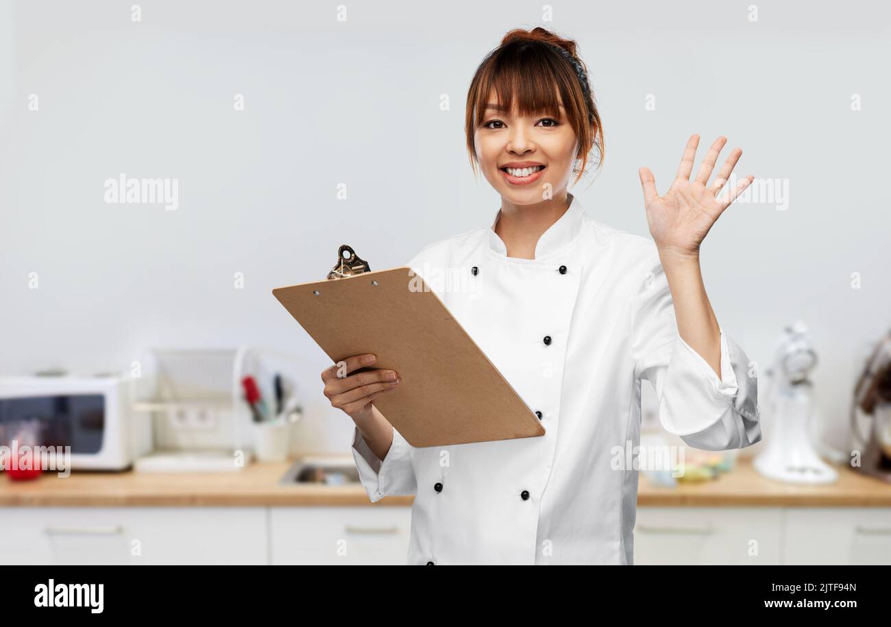 female chef with clipboard waving hand on kitchen Stock Photo - Alamy