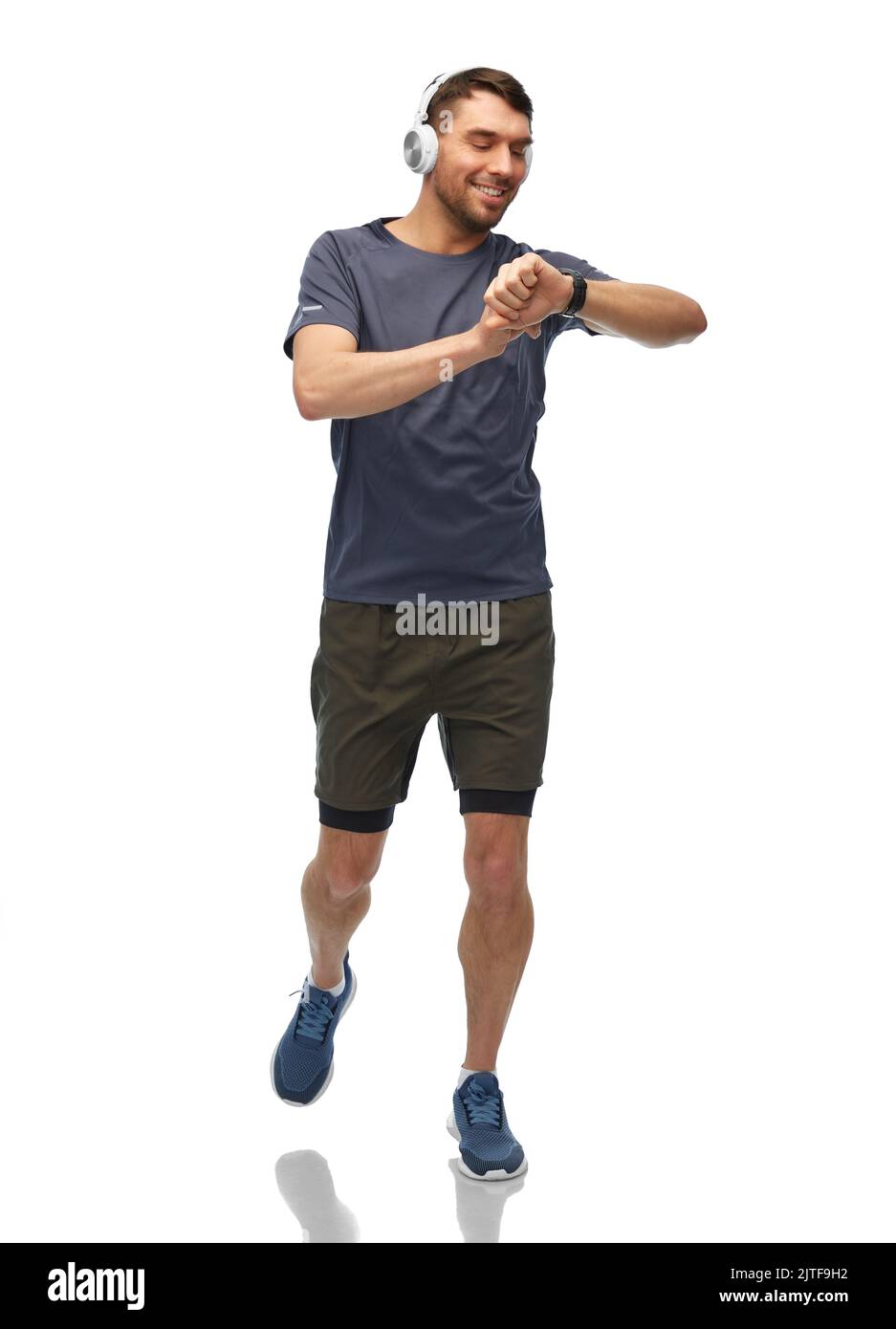 smiling running man in headphones with smart watch Stock Photo - Alamy