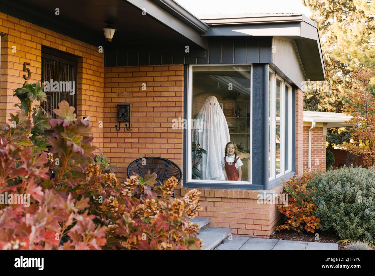 Little girl (2-3) and father dressed as Halloween ghost standing in ...