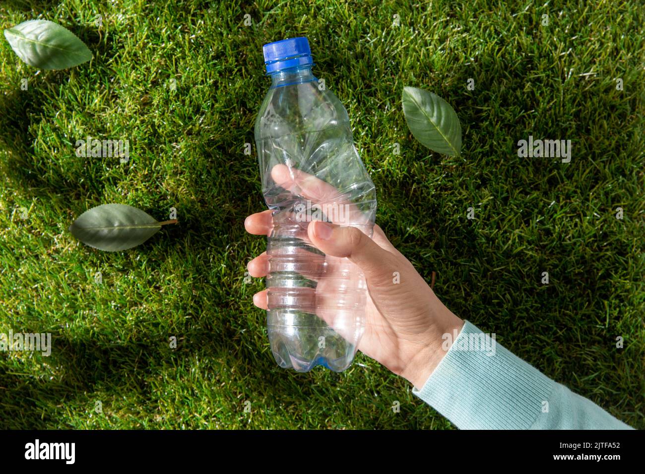 hand removing plastic bottle from grass Stock Photo - Alamy