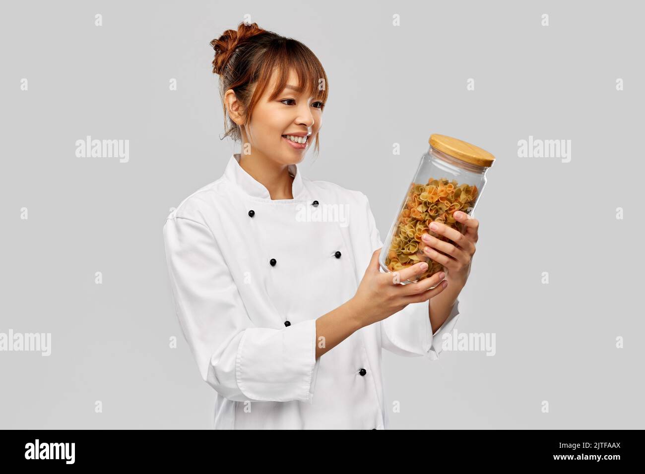 smiling female chef holding jar with pasta Stock Photo - Alamy