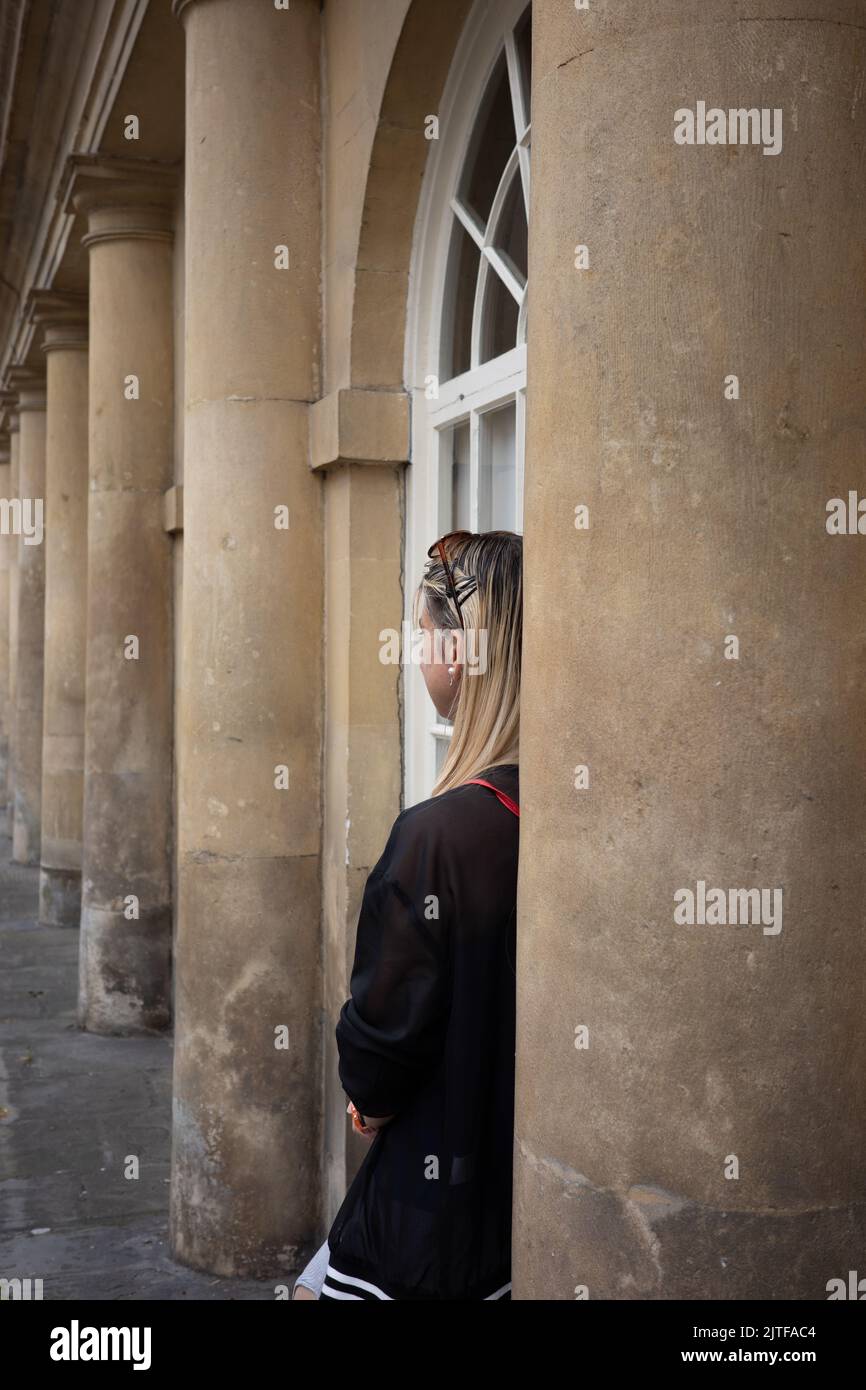 Woman standing between a set of columns in Bath (Aug22 Stock Photo - Alamy