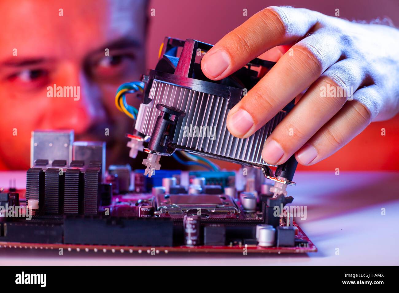 A man's hand inserts a cooler into the motherboard socket, close-up ...