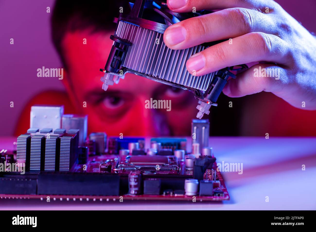 A man's hand inserts a cooler into the motherboard socket, close-up ...