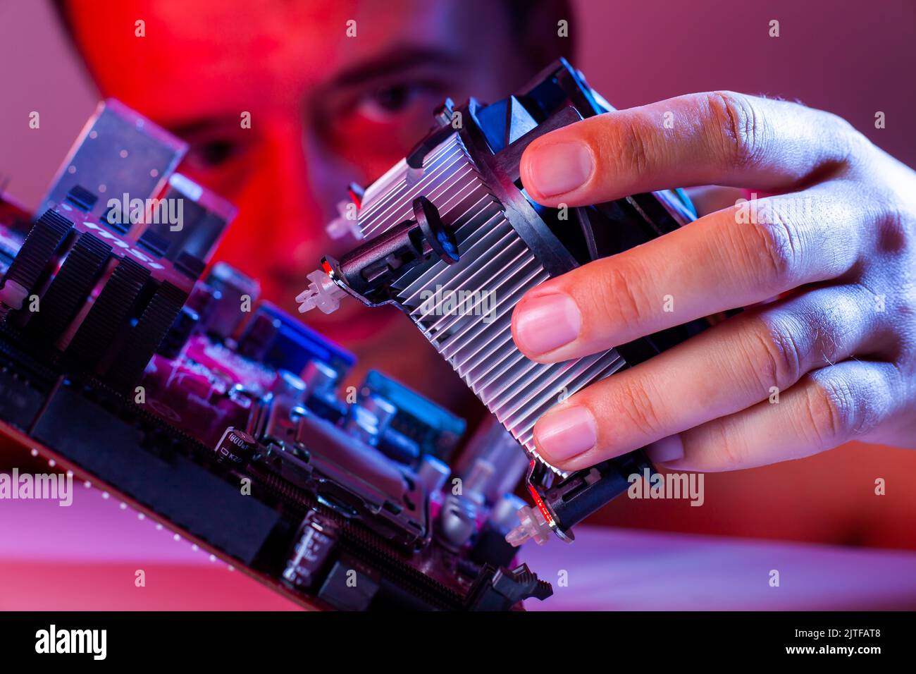 A man's hand inserts a cooler into the motherboard socket, close-up ...