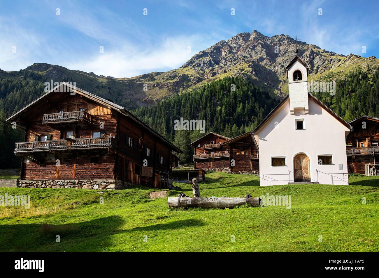White church and wooden cottages of a Oberstalleralm alpine village in ...