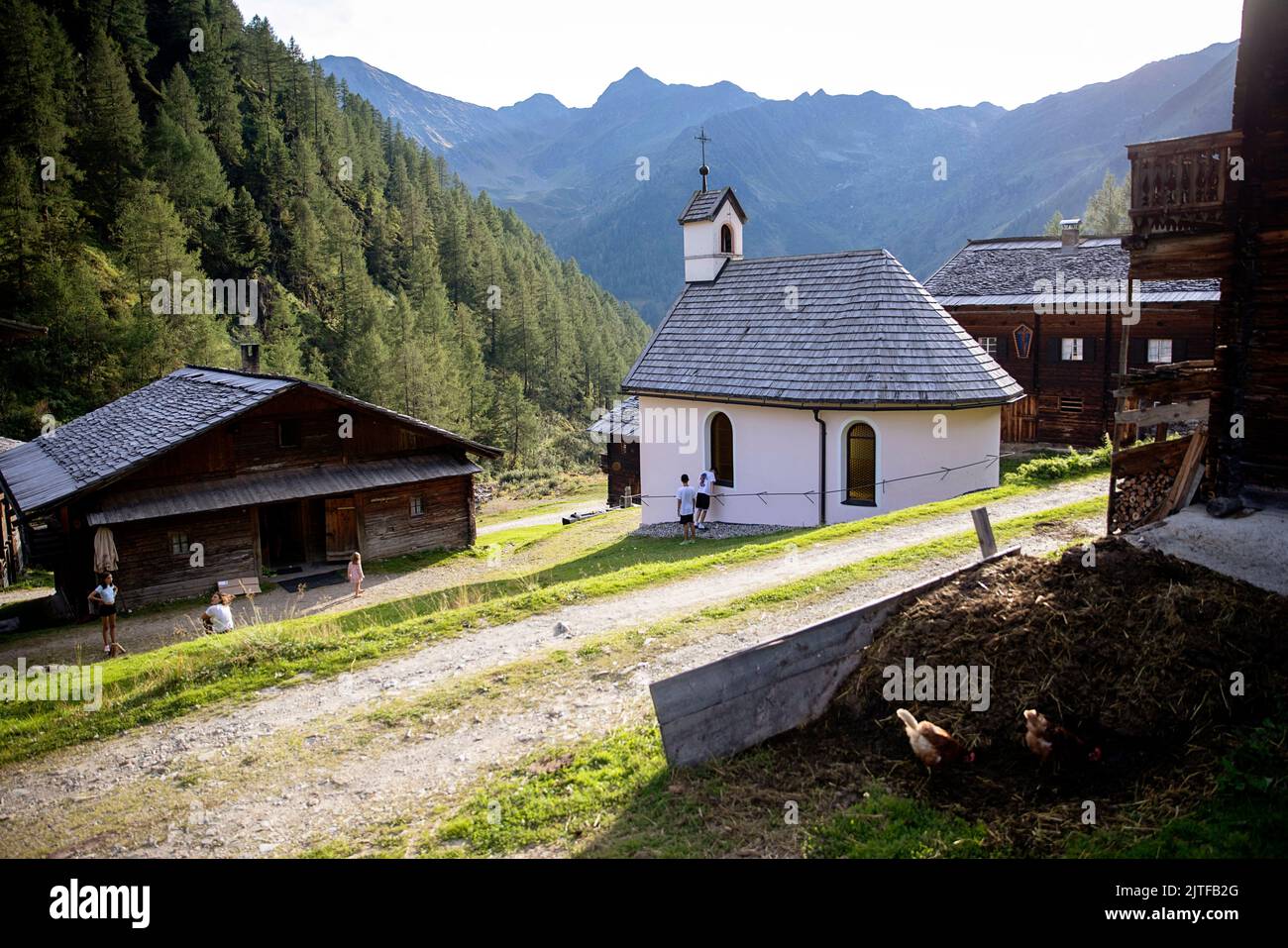 White chapel and wooden huts in a village of Oberstalleralm in austrian ...