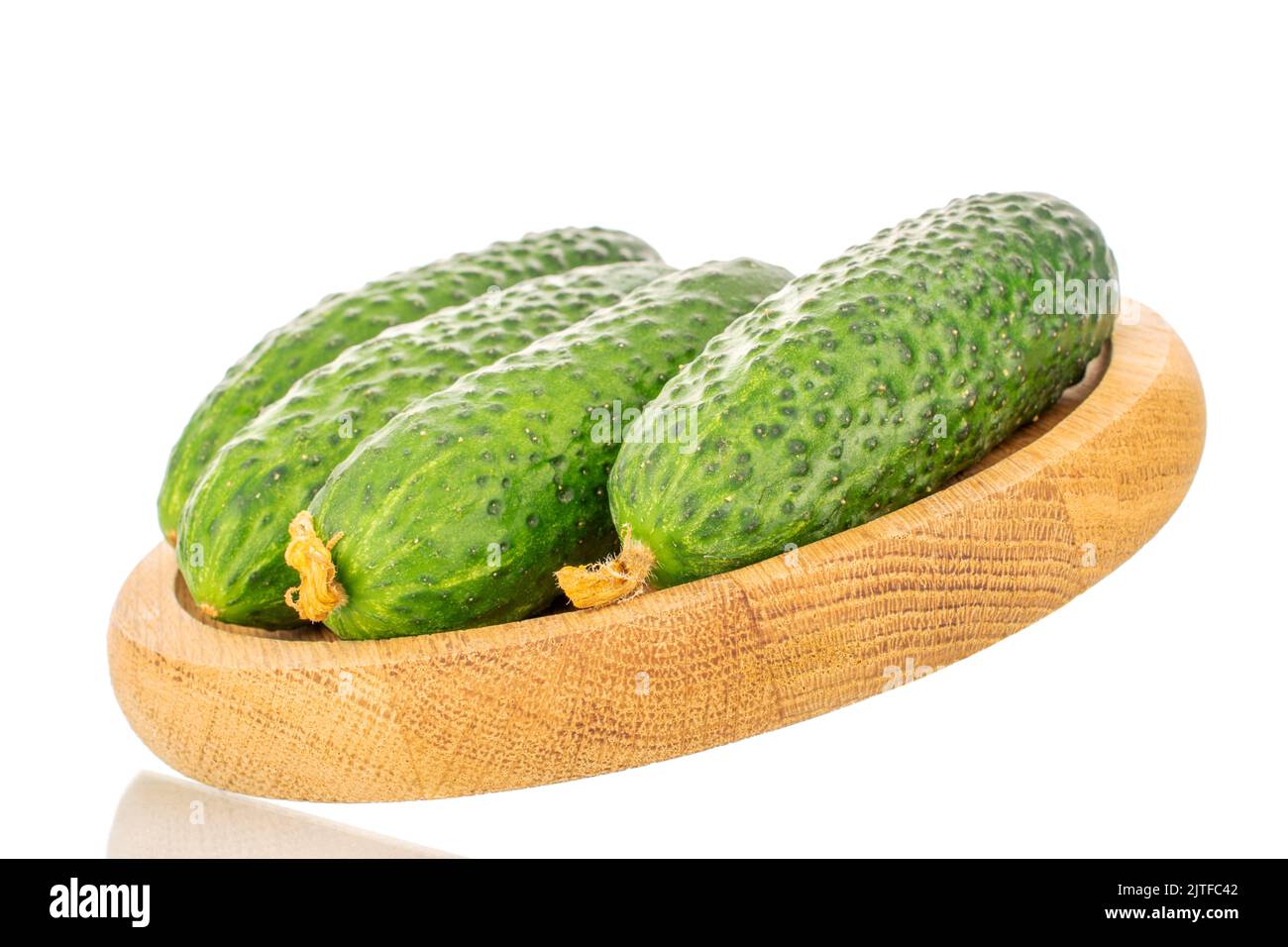 Four organic green cucumbers on a wooden tray, close-up, isolated on a ...
