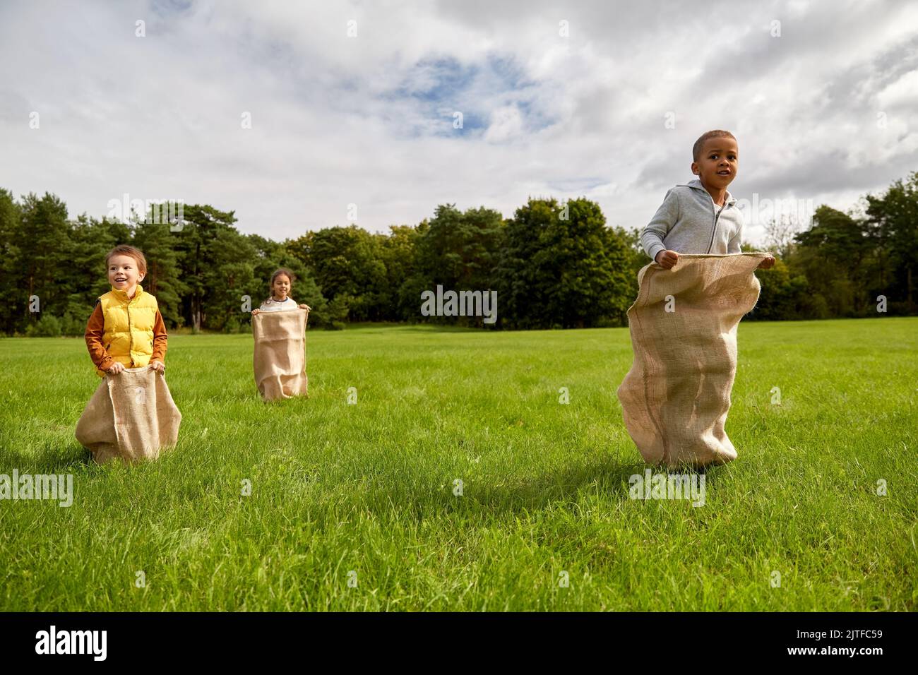 happy children playing bag jumping game at park Stock Photo - Alamy