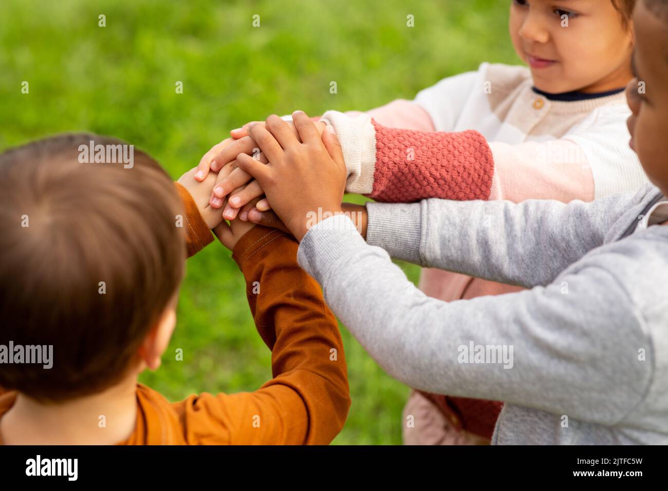 group of children stacking hands at park Stock Photo - Alamy