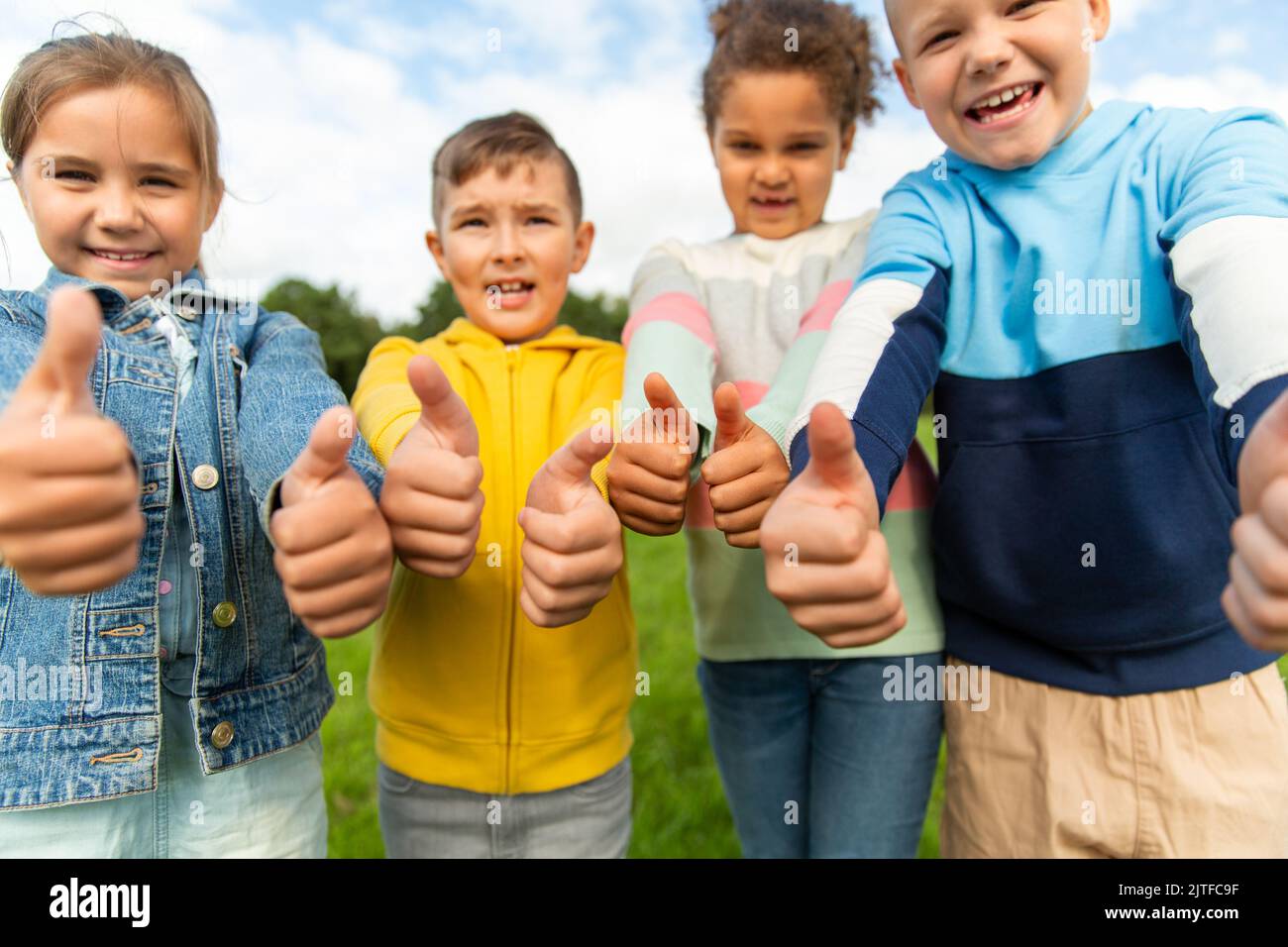 happy children showing thumbs up at park Stock Photo - Alamy