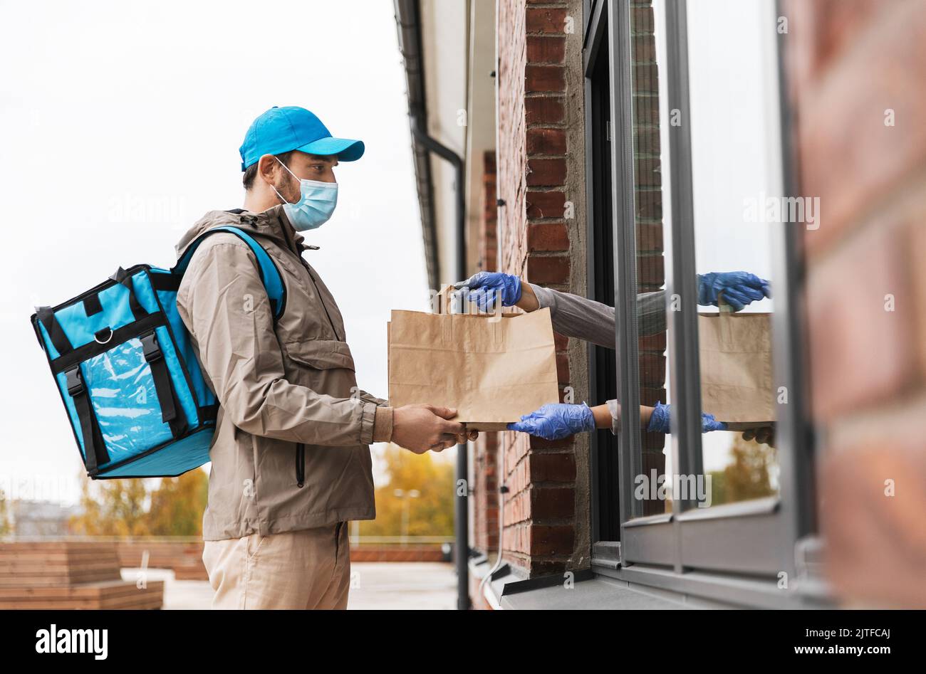 food delivery man in mask giving order to customer Stock Photo - Alamy