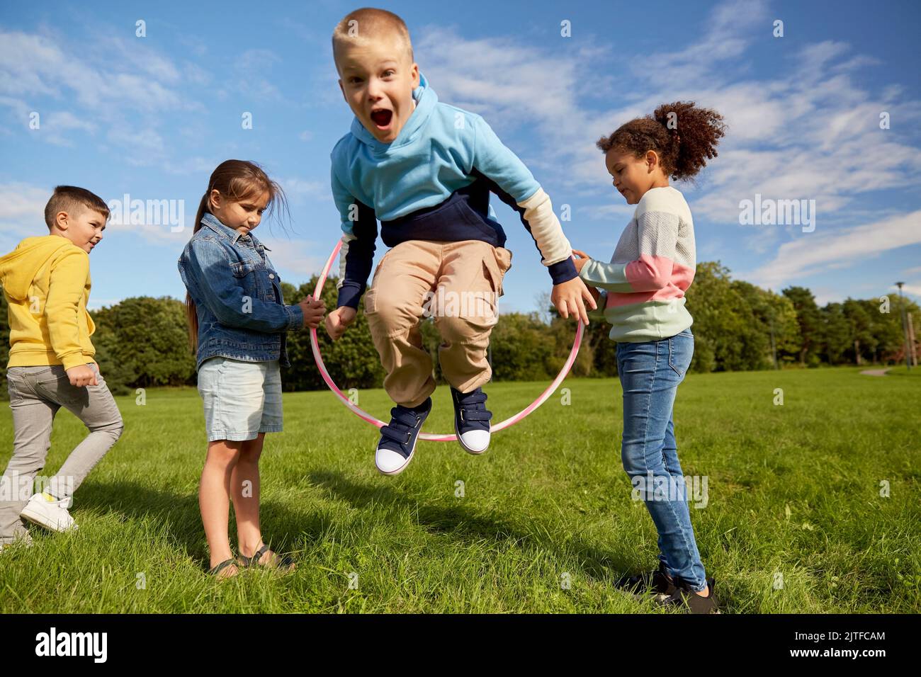 happy children playing game with hula hoop at park Stock Photo - Alamy