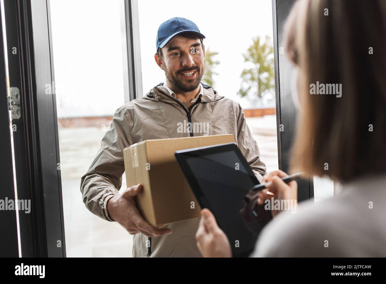 delivery man with box and woman signs digital form Stock Photo - Alamy