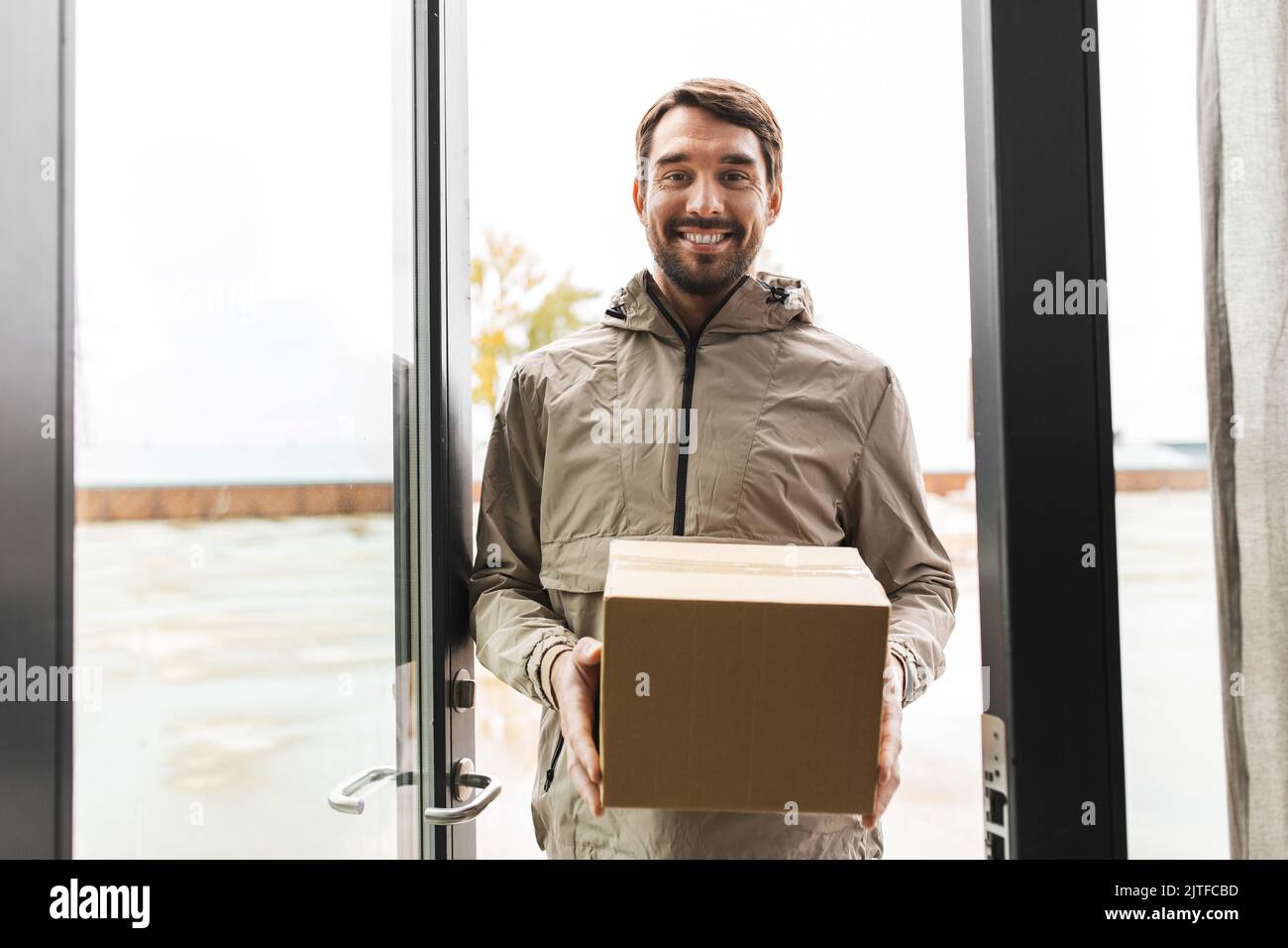 smiling delivery man with parcel box at open door Stock Photo - Alamy