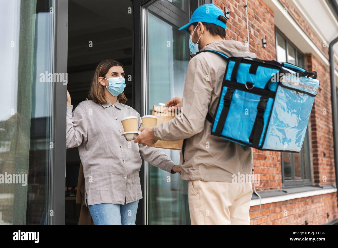 food delivery man in mask giving order to customer Stock Photo - Alamy